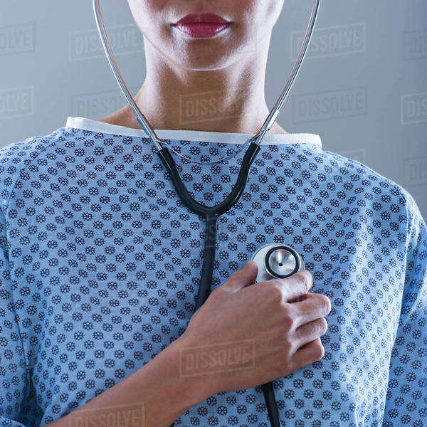 Female patient holding stethoscope to chest - Stock Photo - Dissolve