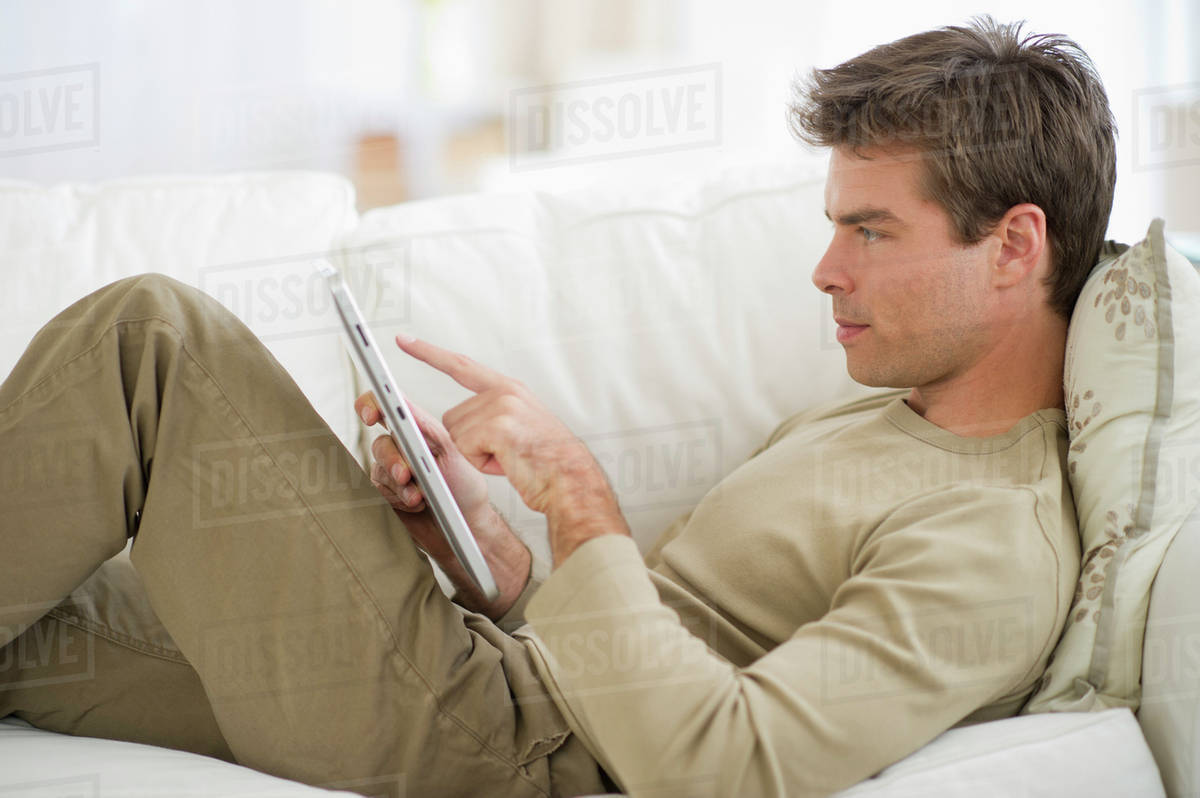 Man sitting on sofa, using digital tablet - Royalty-free Stock Photo ...
