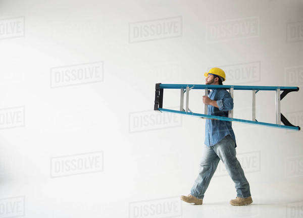 Side view of man carrying ladder - Royalty-free Stock Photo | Dissolve