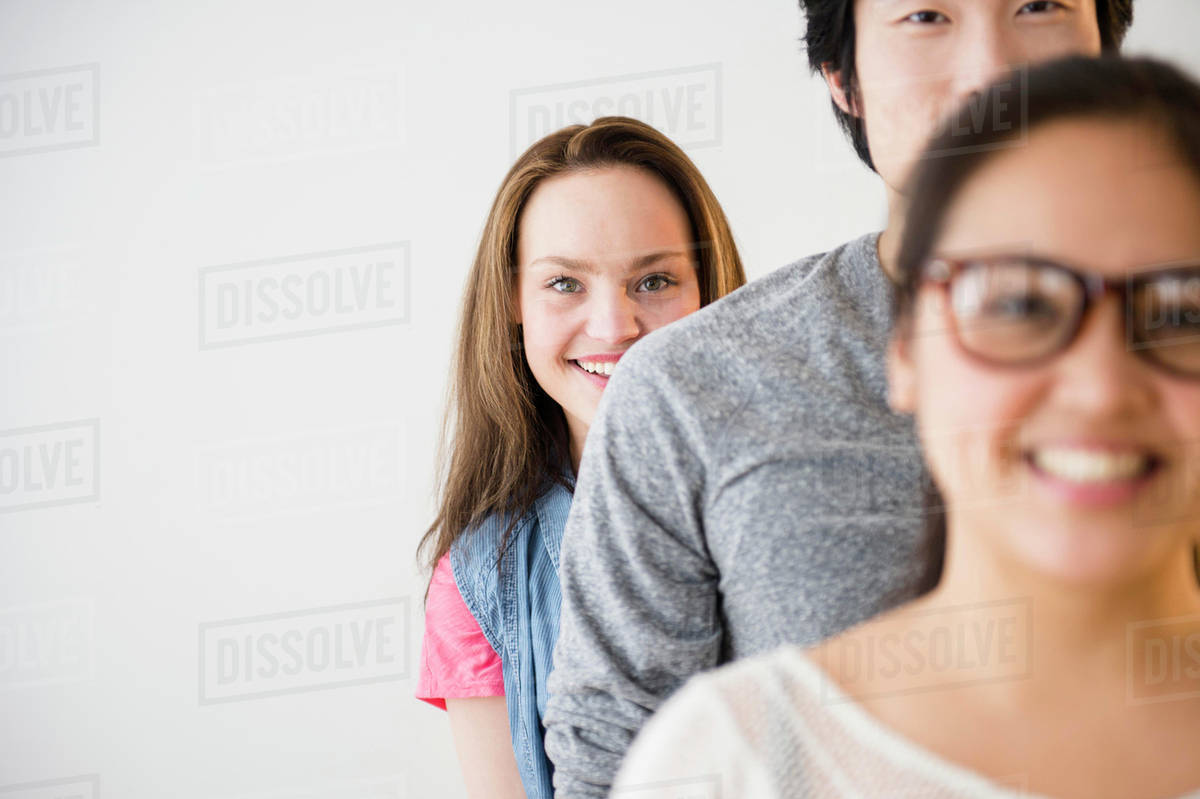 Portrait of young man standing between young women - Stock Photo - Dissolve