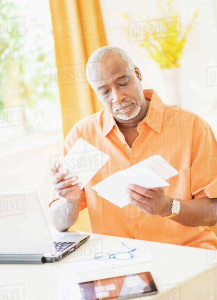 Portrait of man sorting mail at home - Stock Photo - Dissolve
