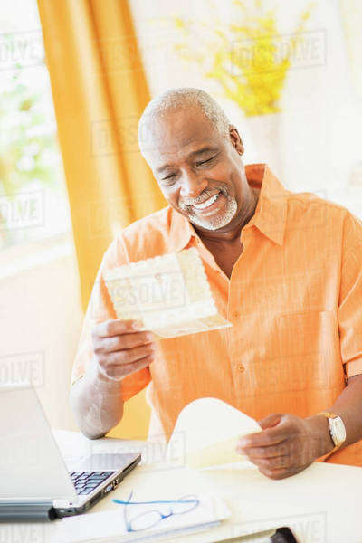 Portrait of man sorting mail at home - Royalty-free Stock Photo | Dissolve