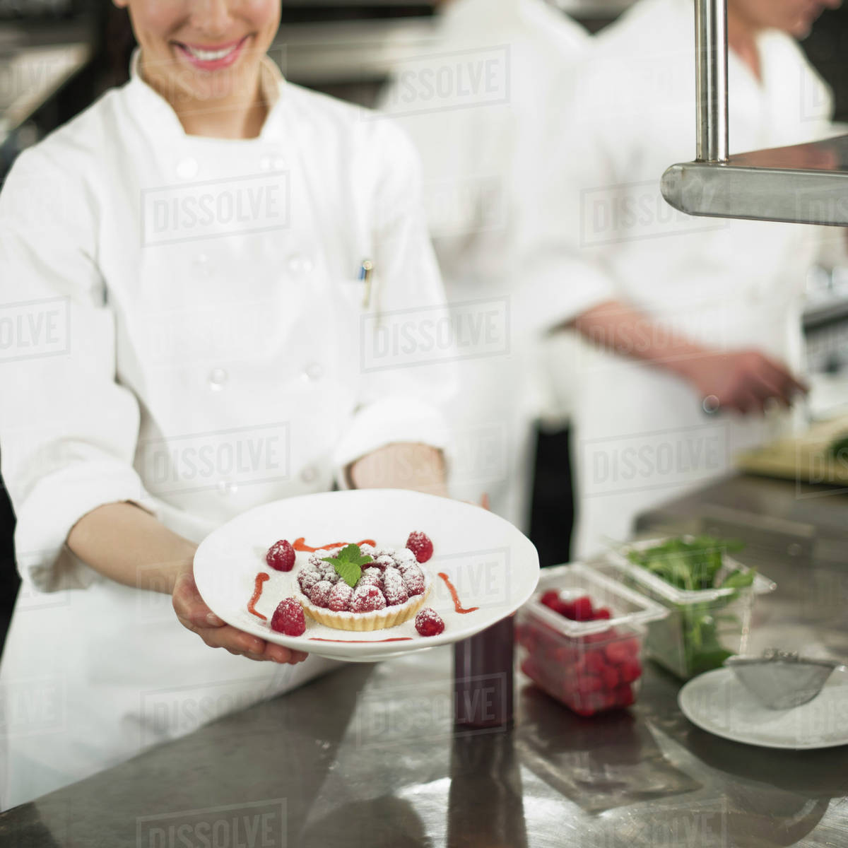 Chefs preparing food in kitchen, women showing dessert - Royalty-free ...