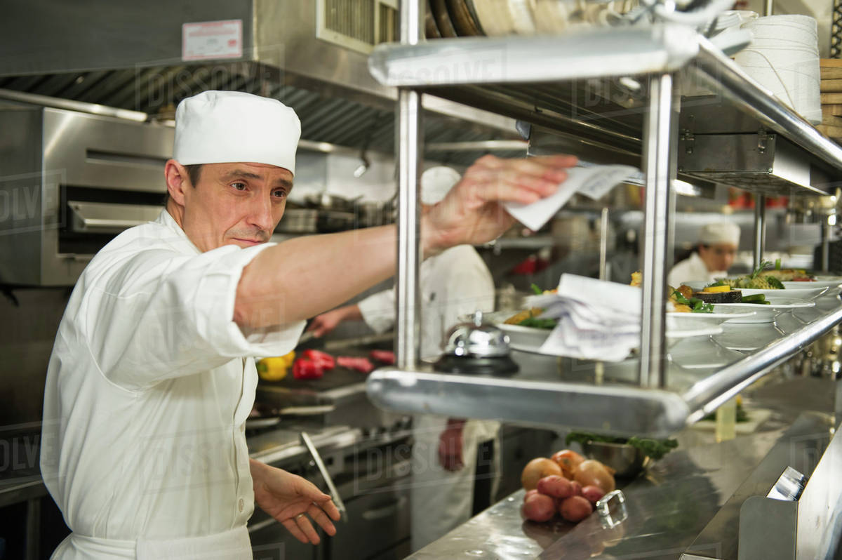 Chef putting order on stick, in background chefs preparing food ...