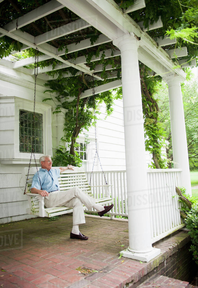 Senior man sitting on porch swing - Royalty-free Stock Photo | Dissolve