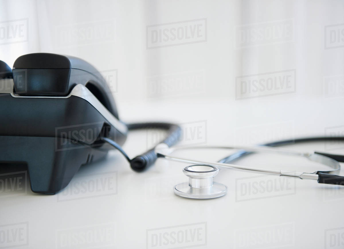 Close up of phone and stethoscope on doctor's desk - Stock Photo - Dissolve