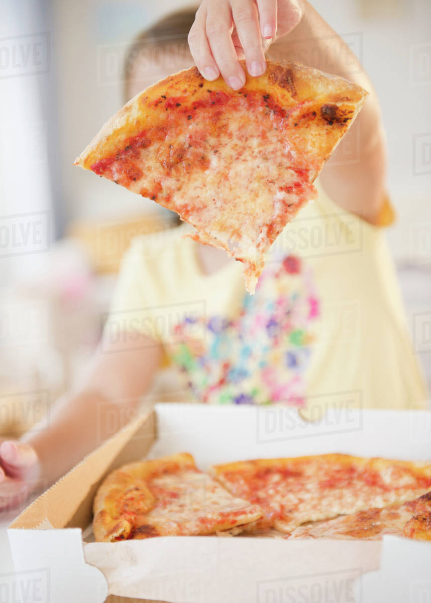 Girl ( 6-7) showing slice of pizza - Royalty-free Stock Photo | Dissolve