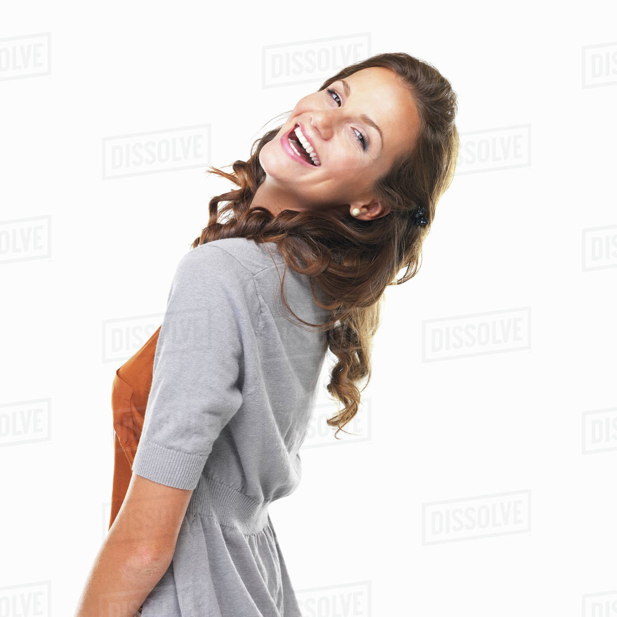 Studio portrait of happy young woman looking over shoulder and smiling ...