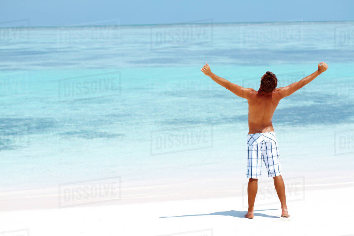 Man standing with his arms wide open on beach - Royalty-free Stock ...