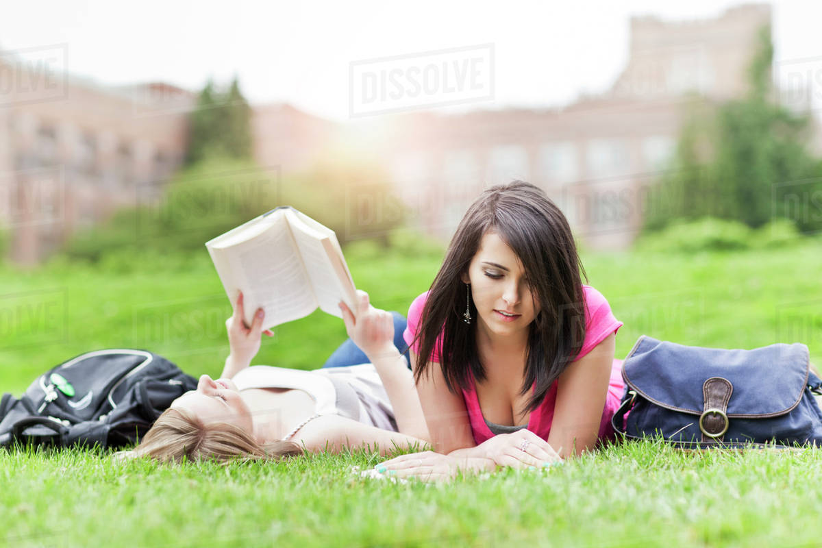 Two female college student lying on grass reading books - Stock Photo ...