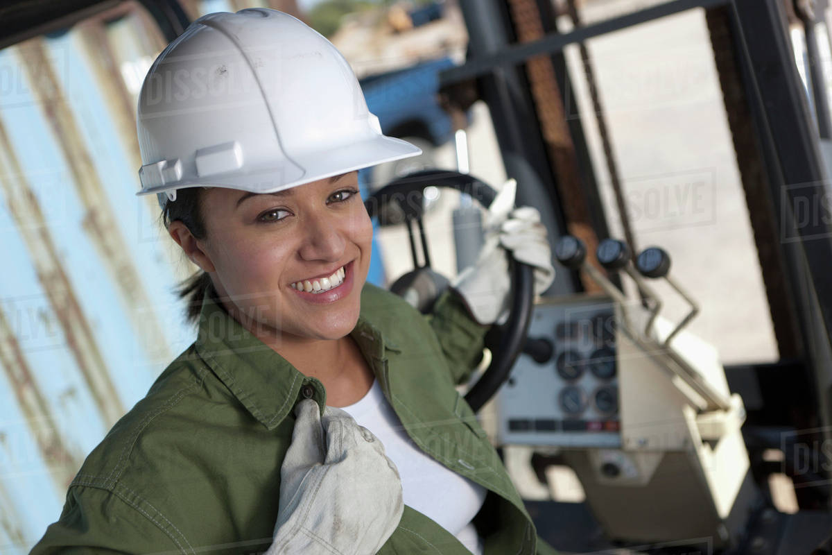 Portrait of female construction worker driving mechanical digger ...