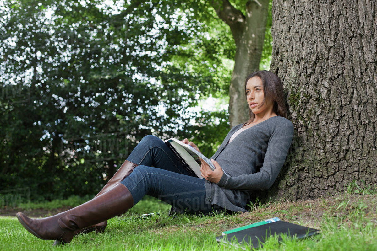 Young woman sitting under tree reading books - Royalty-free Stock Photo ...