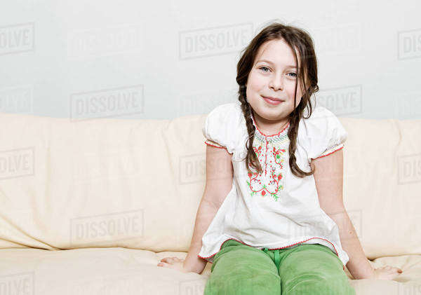Portrait of girl (8-9) sitting on sofa - Royalty-free Stock Photo ...