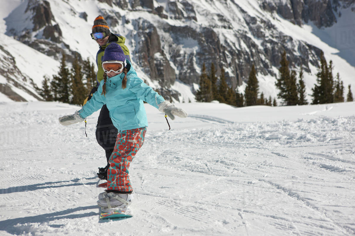 USA, Colorado, Telluride, Father and daughter (10-11) snowboarding ...