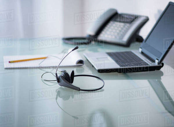 View of headset, telephone, laptop and paper material on desk - Royalty ...