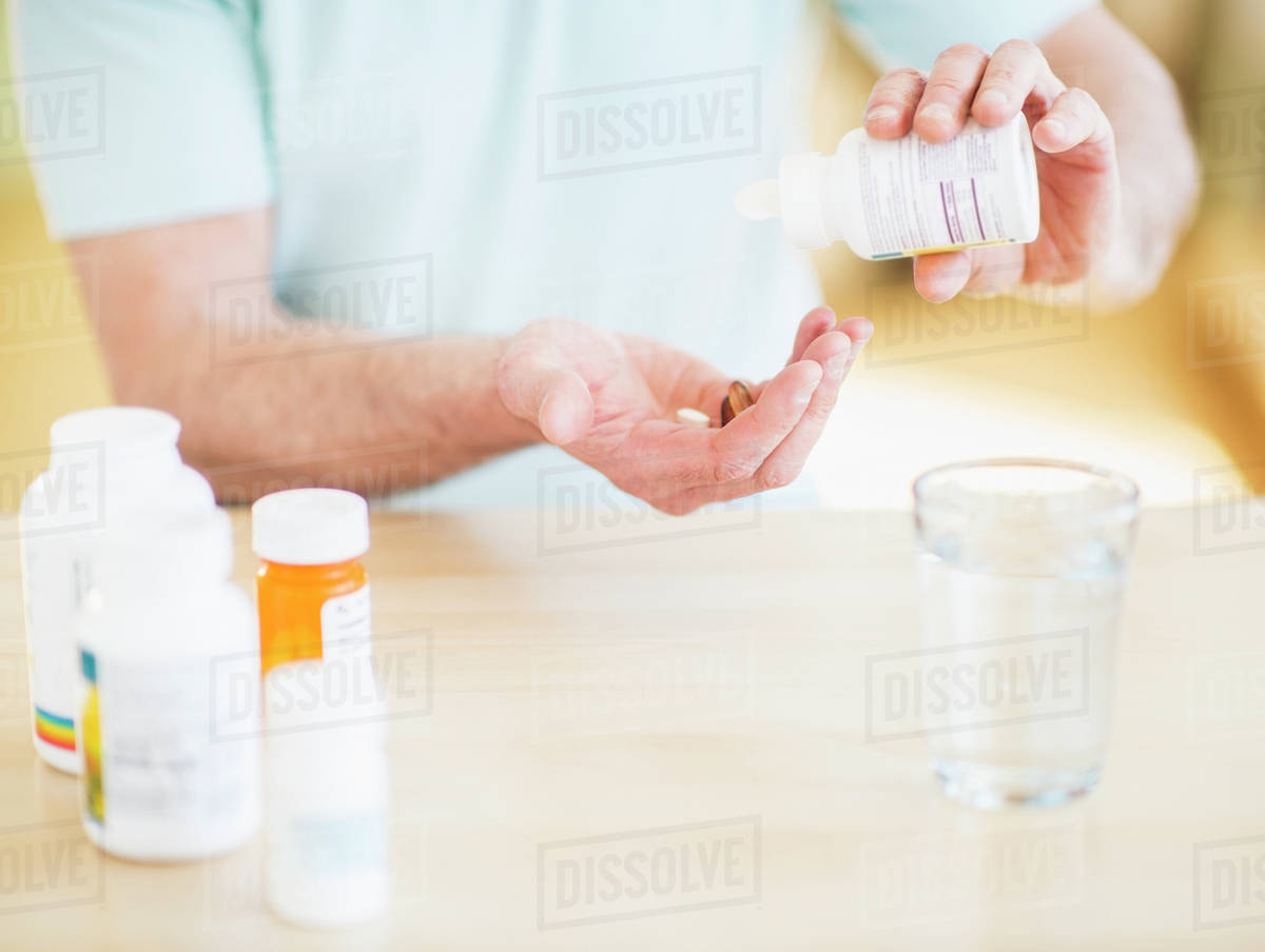 Mid section of man taking medicine - Stock Photo - Dissolve