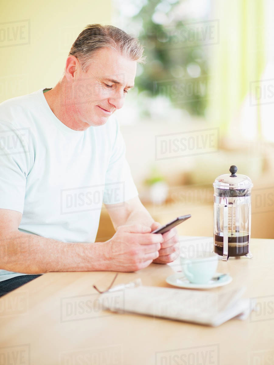 Portrait of man at kitchen table using mobile phone - Stock Photo ...