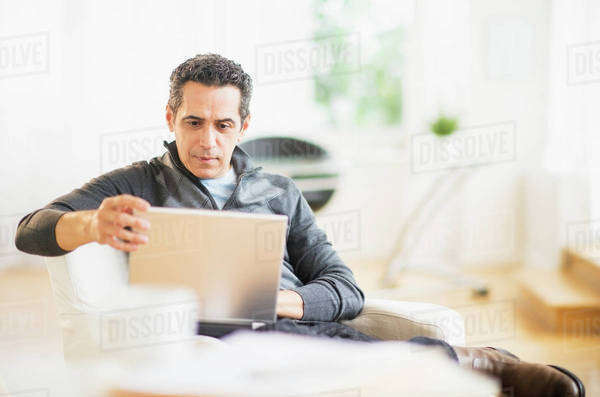 Portrait of man working on laptop at home - Stock Photo - Dissolve