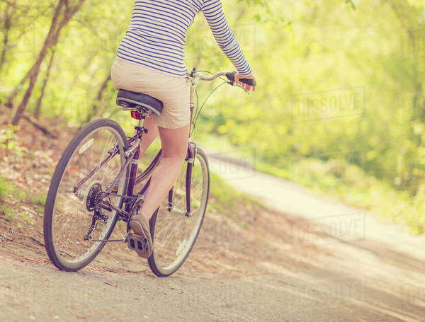Mid adult woman riding bicycle, low section - Stock Photo - Dissolve