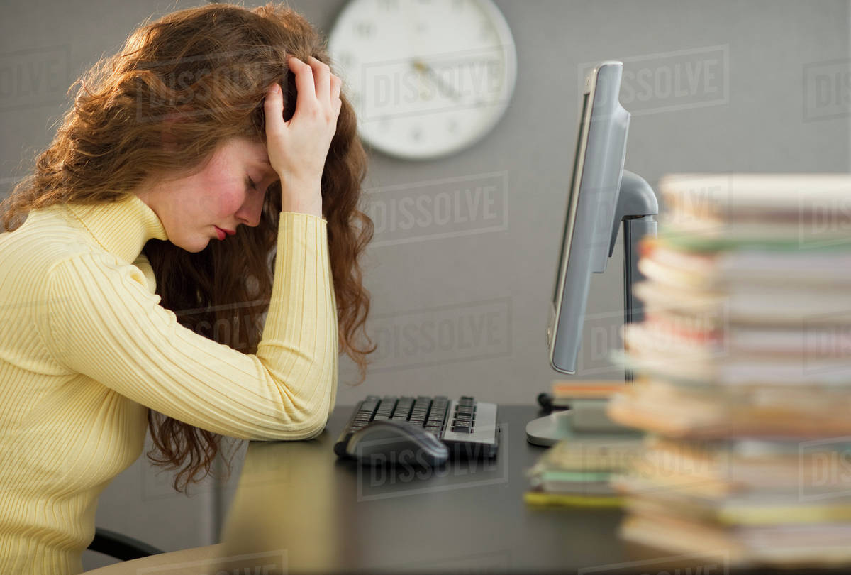 Overworked woman in cubicle - Stock Photo - Dissolve
