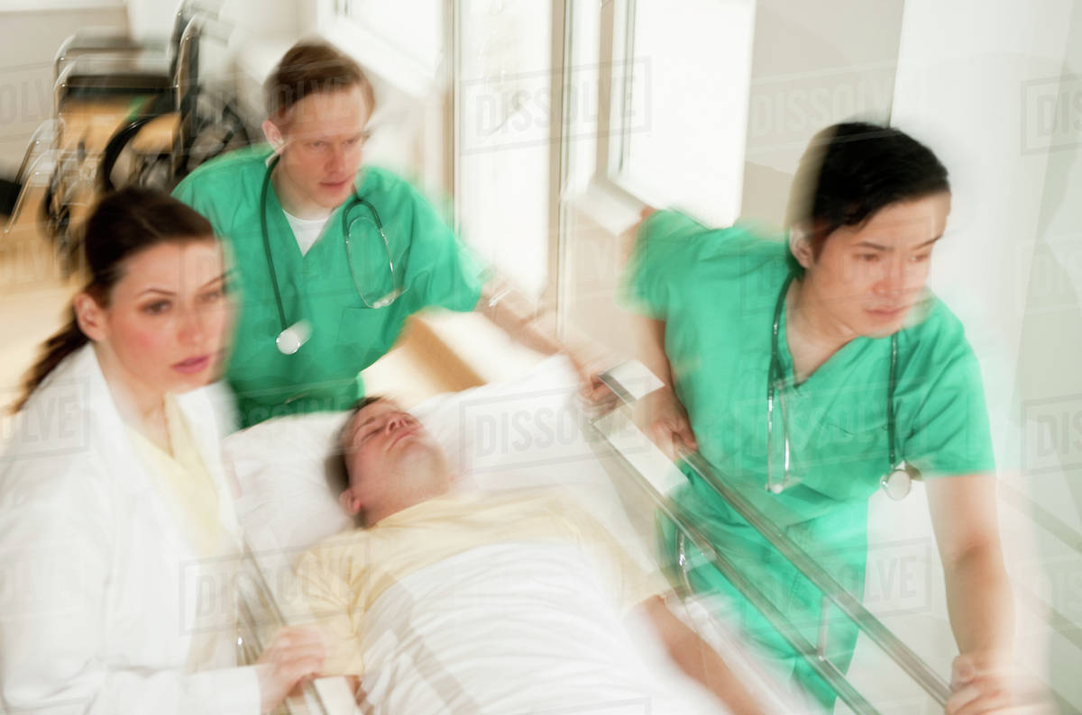 Healthcare workers pushing gurney in emergency room - Royalty-free ...