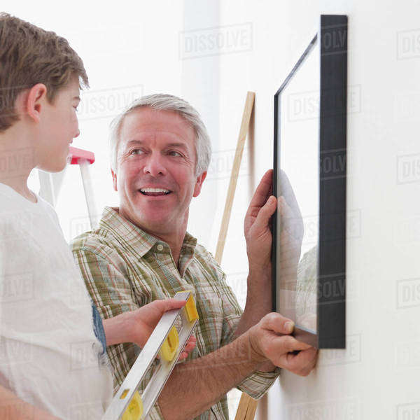 Father and son hanging picture on wall - Stock Photo - Dissolve