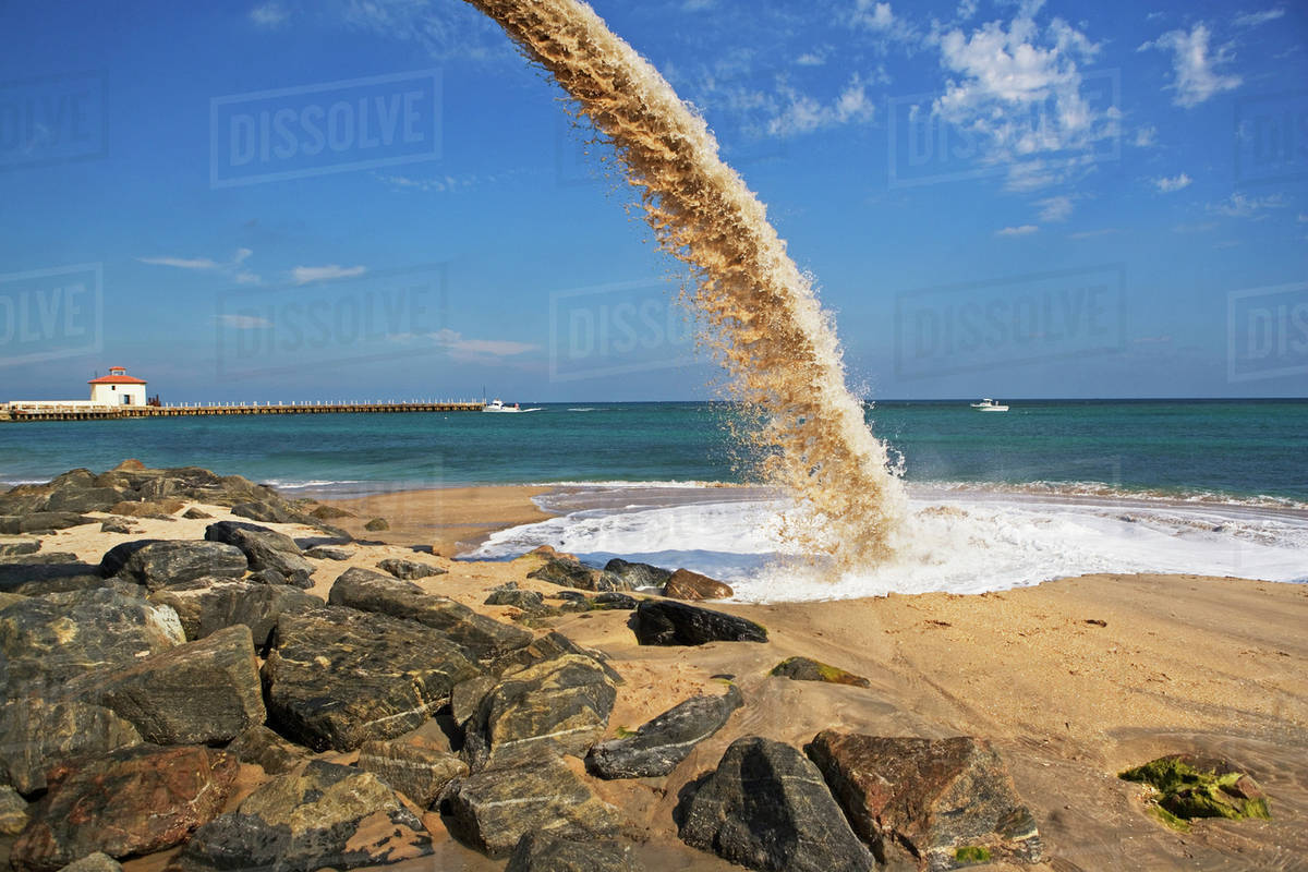 Pipe spraying sand on beach - Stock Photo - Dissolve