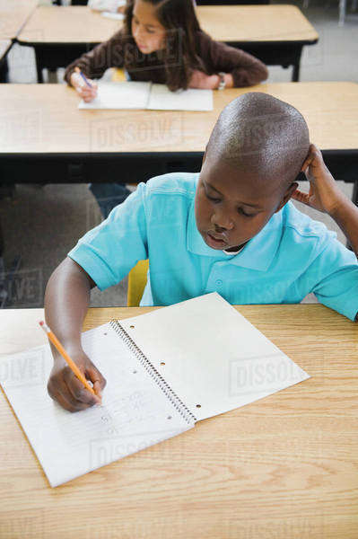 Elementary students writing in notebooks at their desks - Royalty-free ...