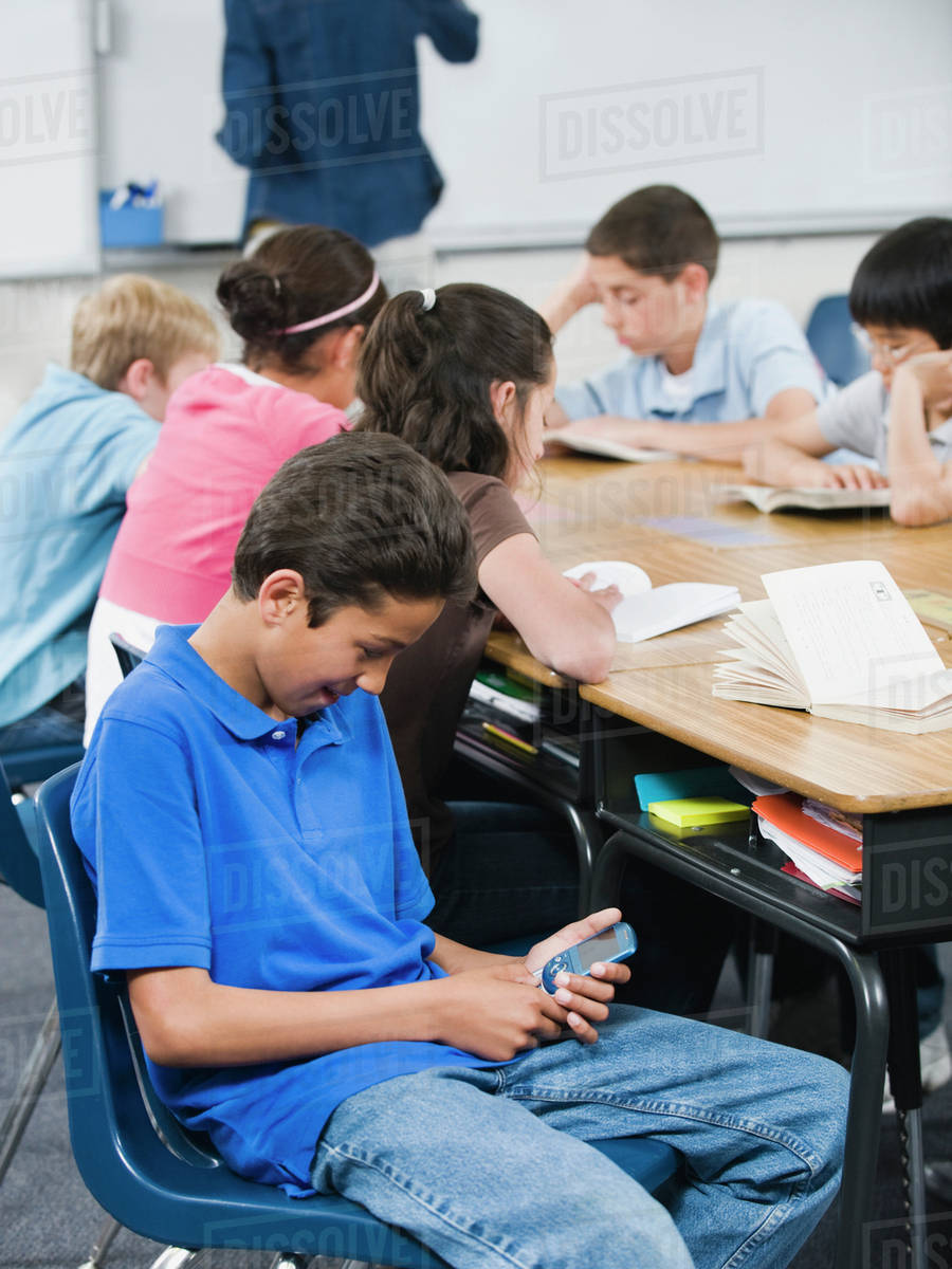 Student texting in classroom - Royalty-free Stock Photo | Dissolve