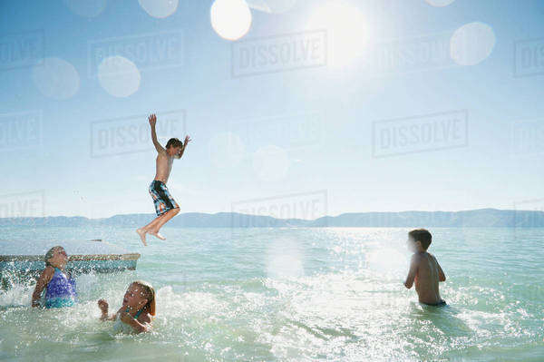 Kids (6-7,8-9,10-11,12-13) playing on raft on lake - Stock Photo - Dissolve