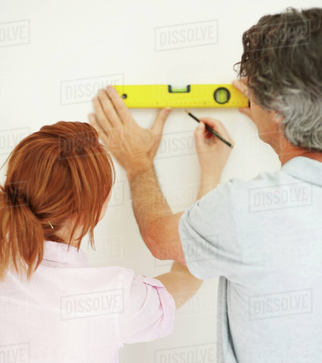 Couple marking a straight line on wall - Stock Photo - Dissolve