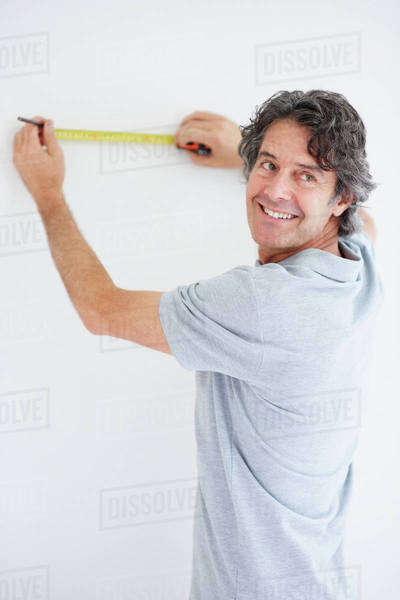 Carpenter marking straight line on wall - Stock Photo - Dissolve