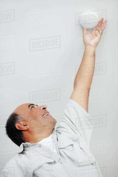 Man reaching up to smoke detector - Royalty-free Stock Photo | Dissolve