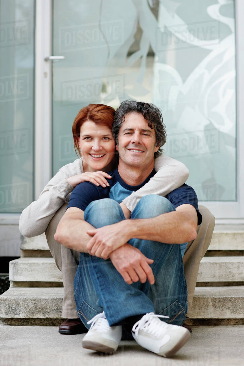 Couple sitting on steps in front of their home - Royalty-free Stock ...
