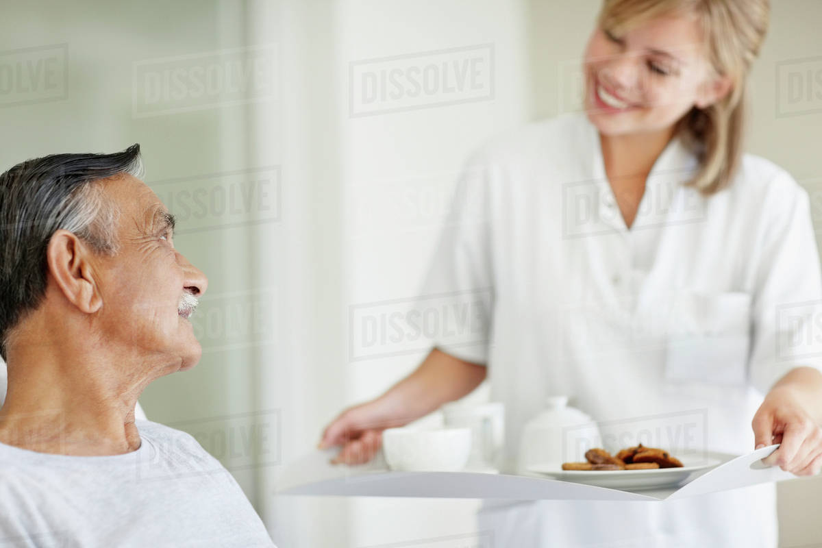 Nurse giving tray of food to patient - Stock Photo - Dissolve