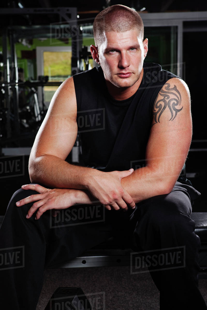 Mad adult man sitting in gym - Royalty-free Stock Photo | Dissolve