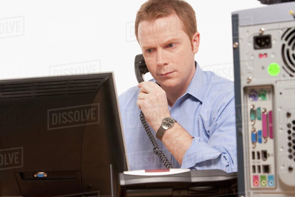 Businessman talking on phone while looking at computer - Royalty-free ...