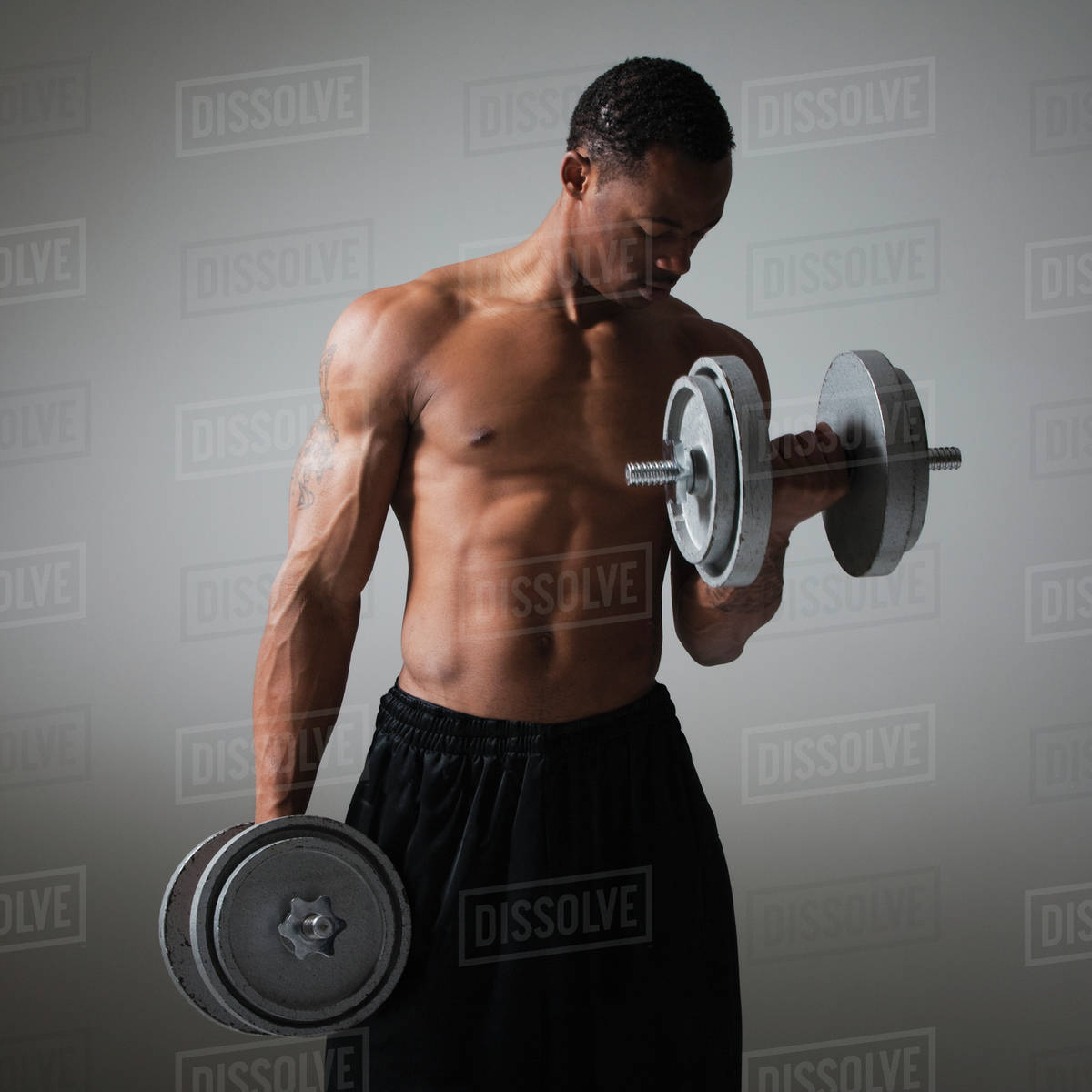 Muscular man lifting dumbbells - Stock Photo - Dissolve