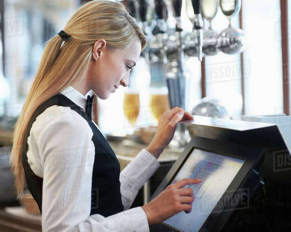 Young waitress using computer at restaurant counter - Royalty-free ...