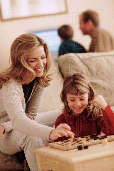 Mother and daughter playing checkers - Stock Photo - Dissolve
