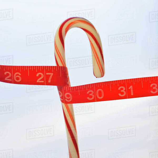 Measuring tape around candy cane - Stock Photo - Dissolve