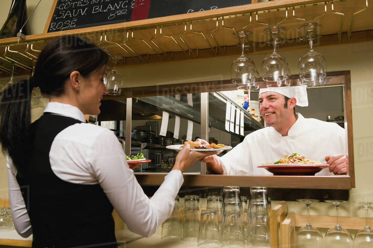 Chef giving waitress plates of food - Stock Photo - Dissolve