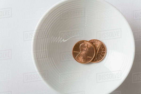 Two one cent coins in bowl - Royalty-free Stock Photo | Dissolve