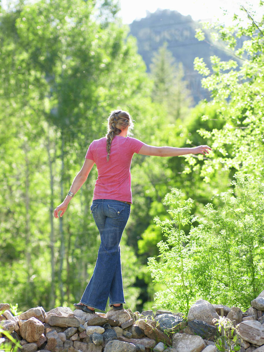 Woman walking on stone barrier - Royalty-free Stock Photo | Dissolve