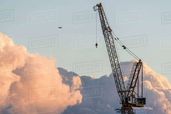 Crane with airplane in background at sunset - Stock Photo - Dissolve