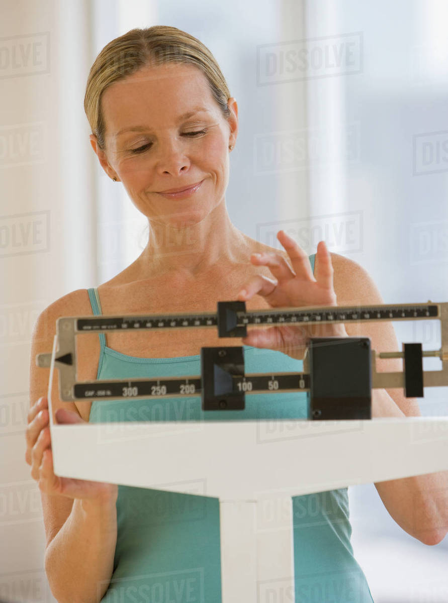 Woman weighing self on scale - Stock Photo - Dissolve