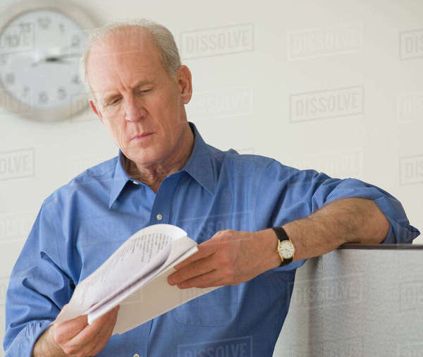 Senior businessman reading paperwork - Stock Photo - Dissolve