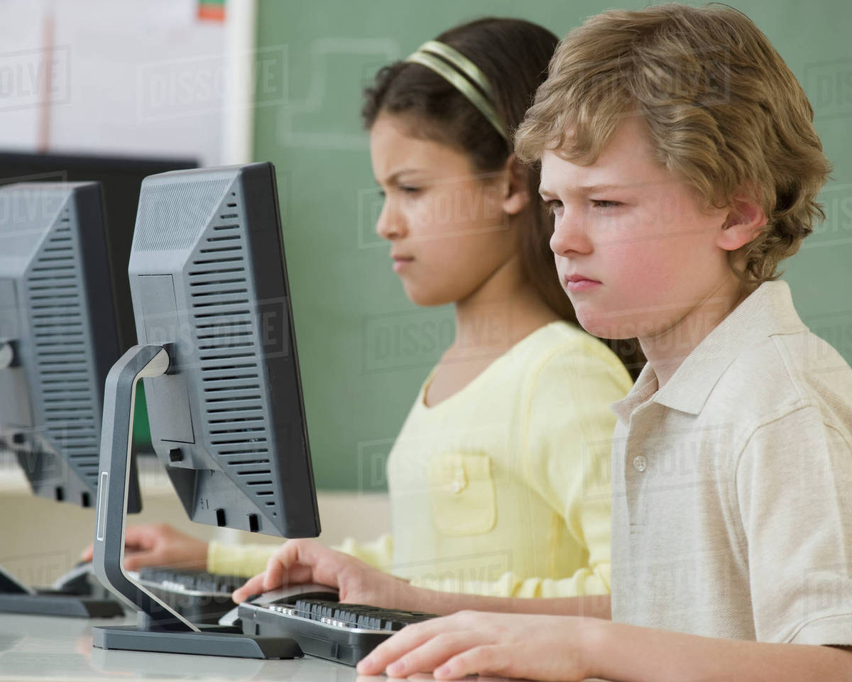 Multi-ethnic school children looking at computers - Stock Photo - Dissolve
