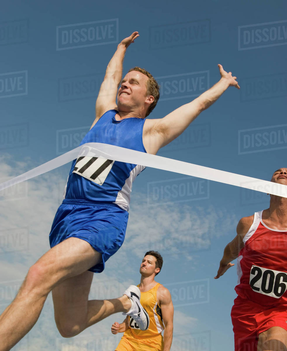 Runner breaking through finish line - Royalty-free Stock Photo | Dissolve