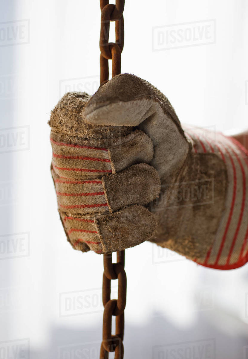 Close up of gloved hand holding chain - Royalty-free Stock Photo | Dissolve